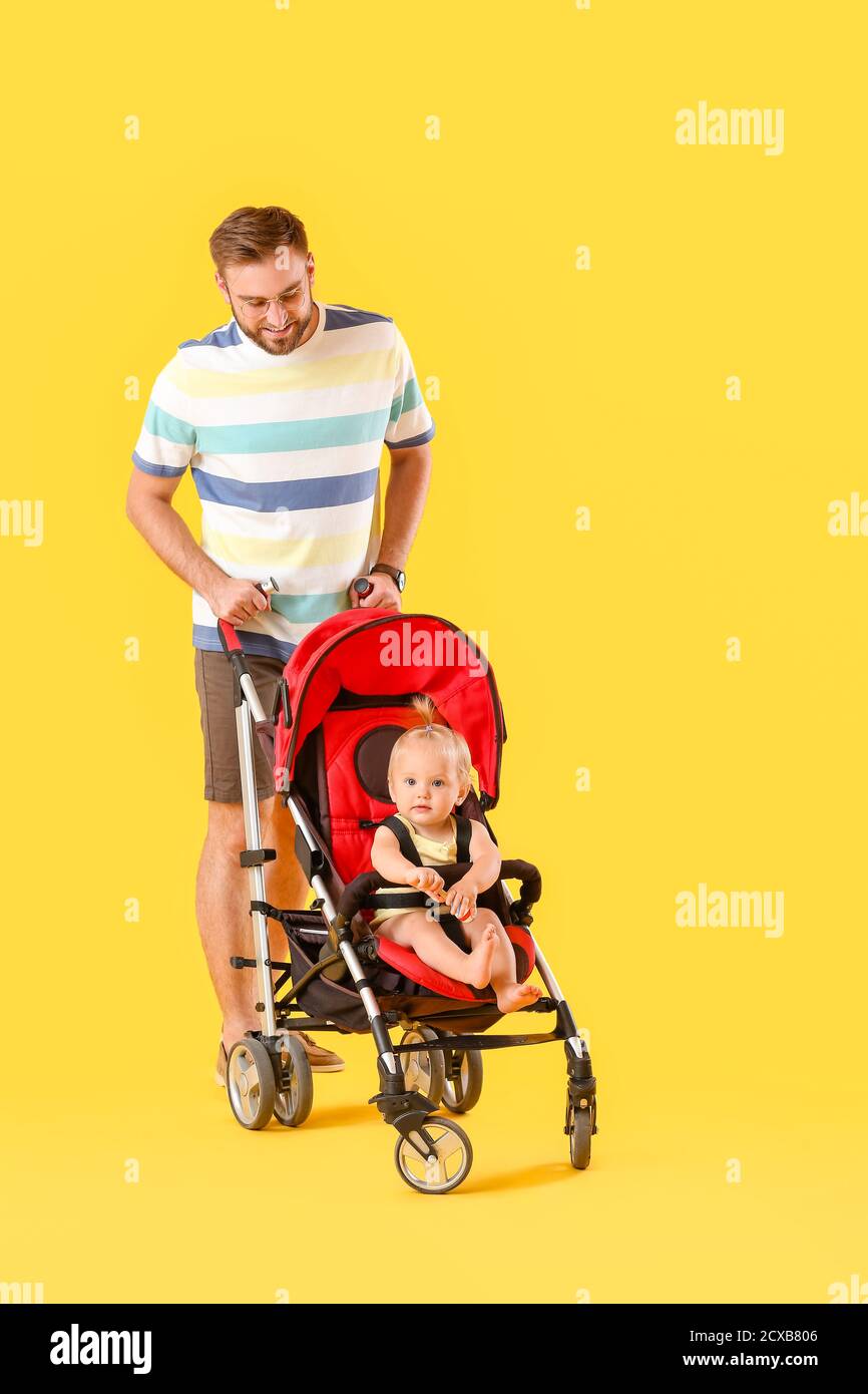 Father and his cute baby in stroller on color background Stock Photo ...