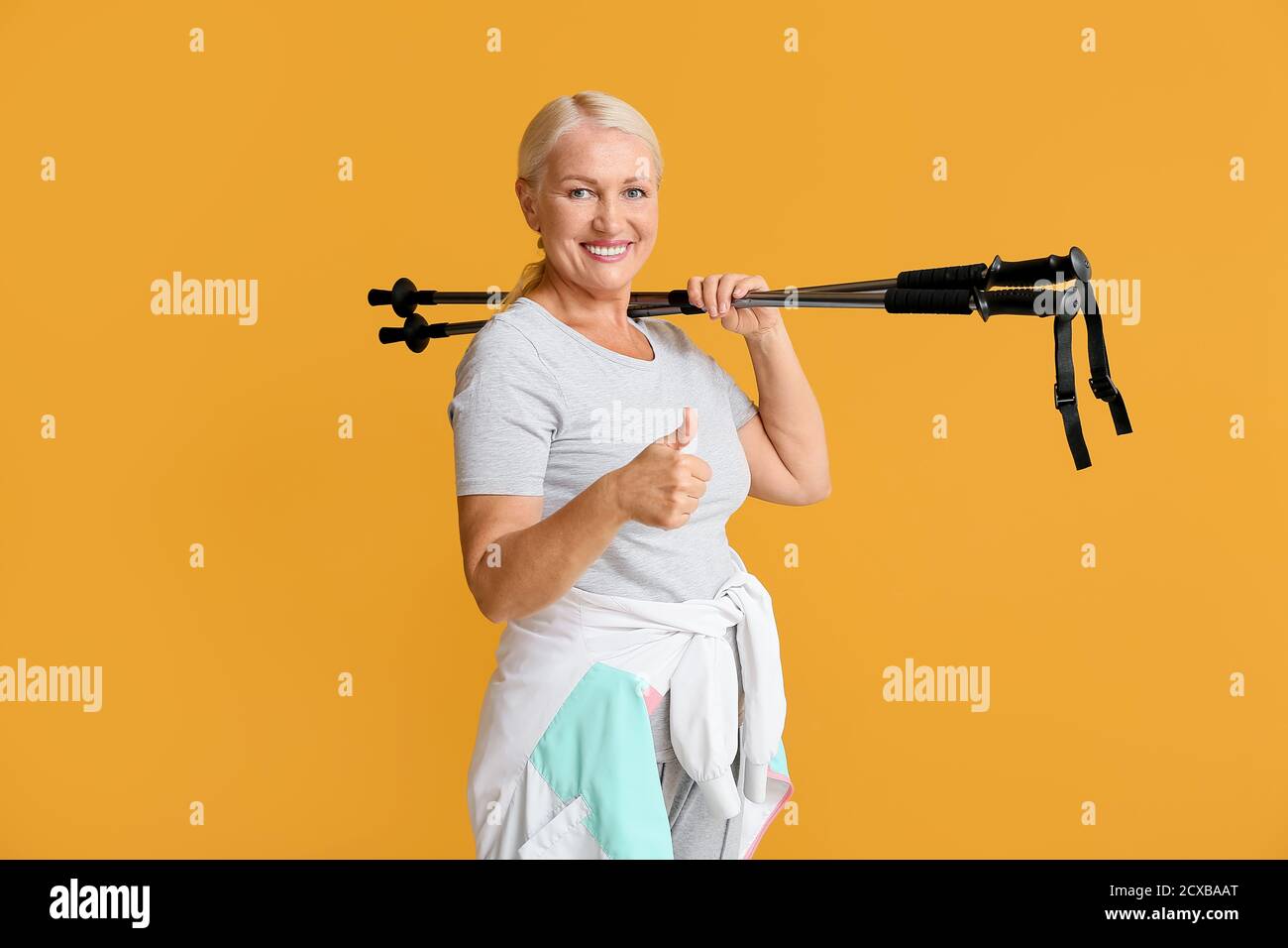 Mature woman with walking poles on color background Stock Photo - Alamy
