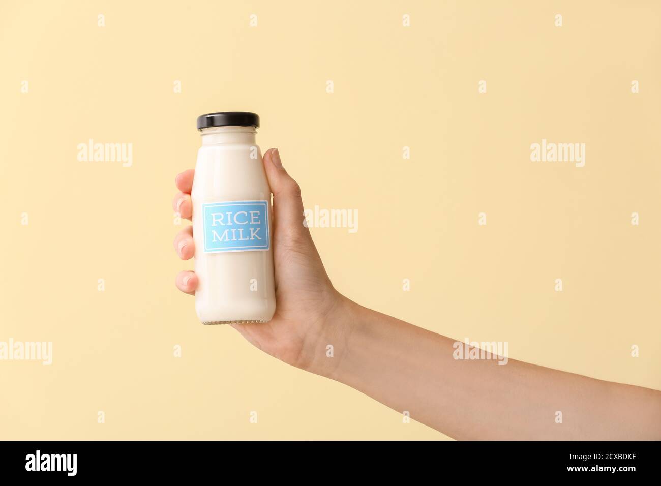 Female hand with bottle of rice milk on color background Stock Photo ...