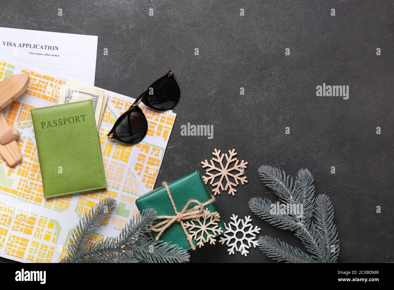 Composition with Christmas gift, passport, map and sunglasses on dark ...