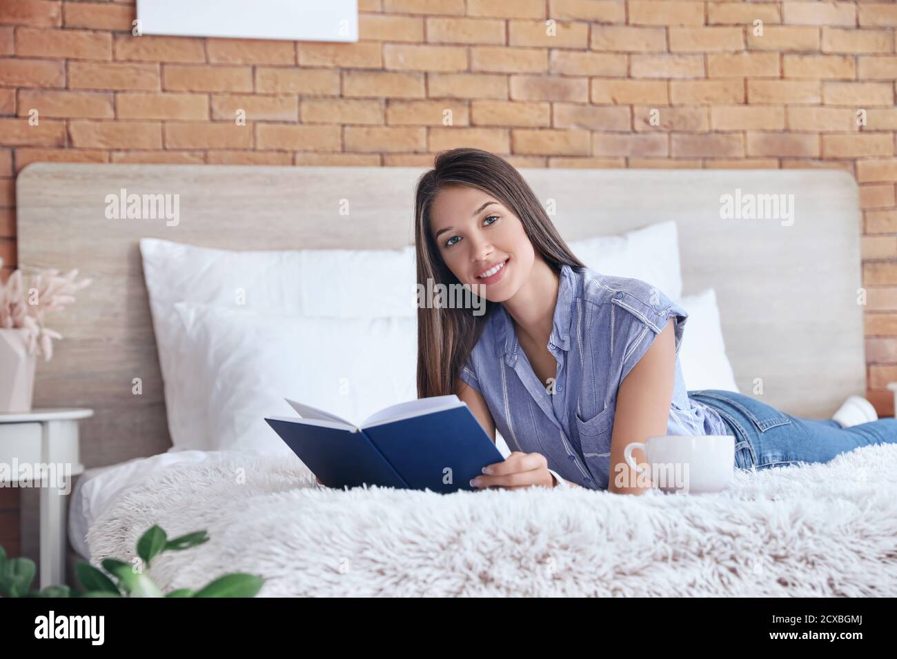 Beautiful young woman reading book at home Stock Photo - Alamy