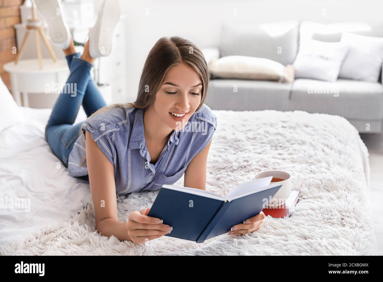 Beautiful young woman reading book at home Stock Photo - Alamy