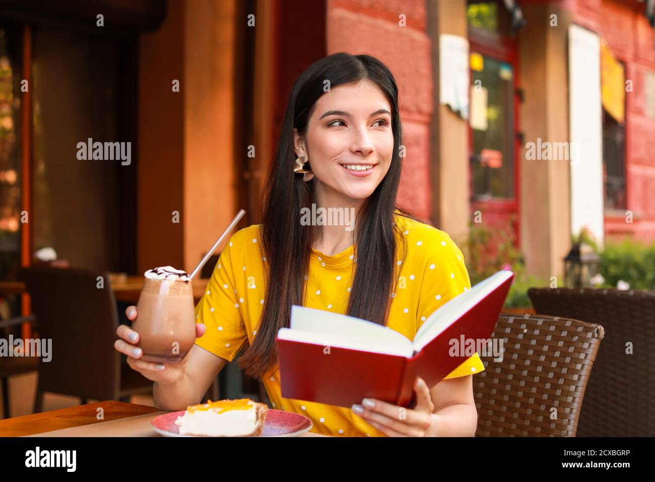 Beautiful young woman reading book in street cafe Stock Photo - Alamy