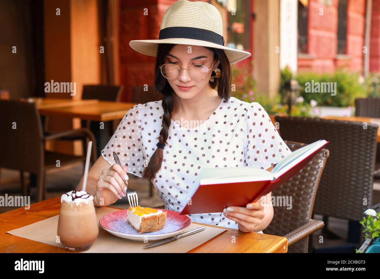 Beautiful young woman reading book in street cafe Stock Photo - Alamy