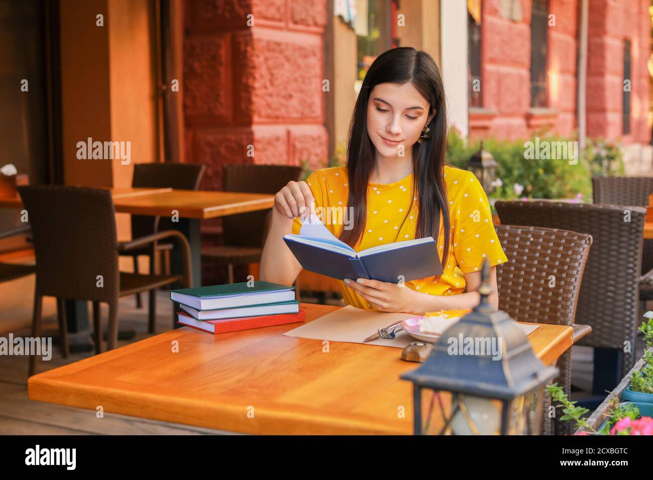 Beautiful young woman reading book in street cafe Stock Photo - Alamy