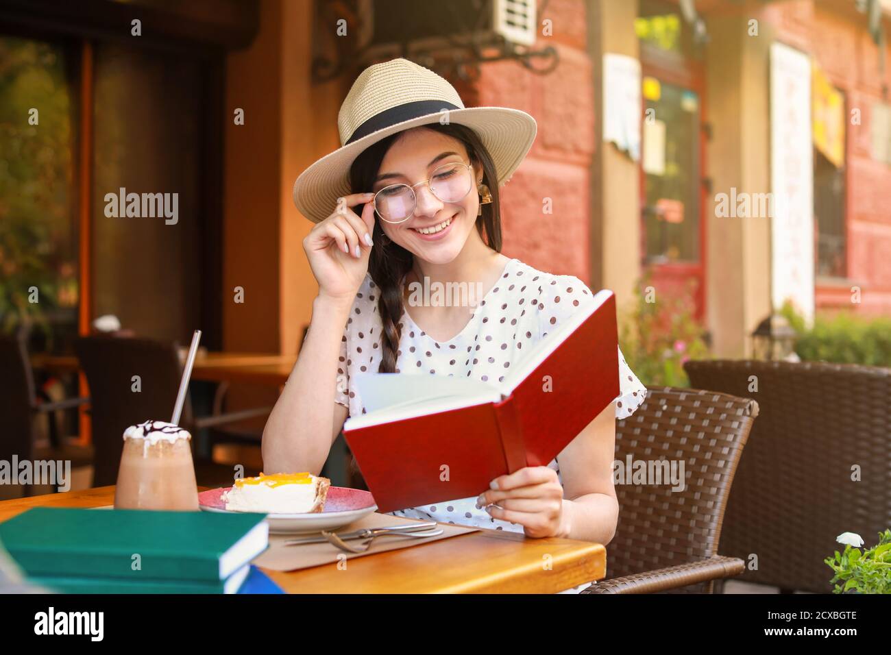 Beautiful young woman reading book in street cafe Stock Photo - Alamy