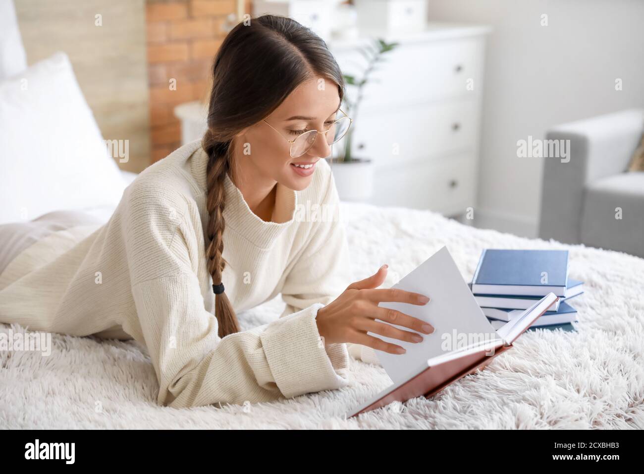 Beautiful young woman reading book at home Stock Photo - Alamy