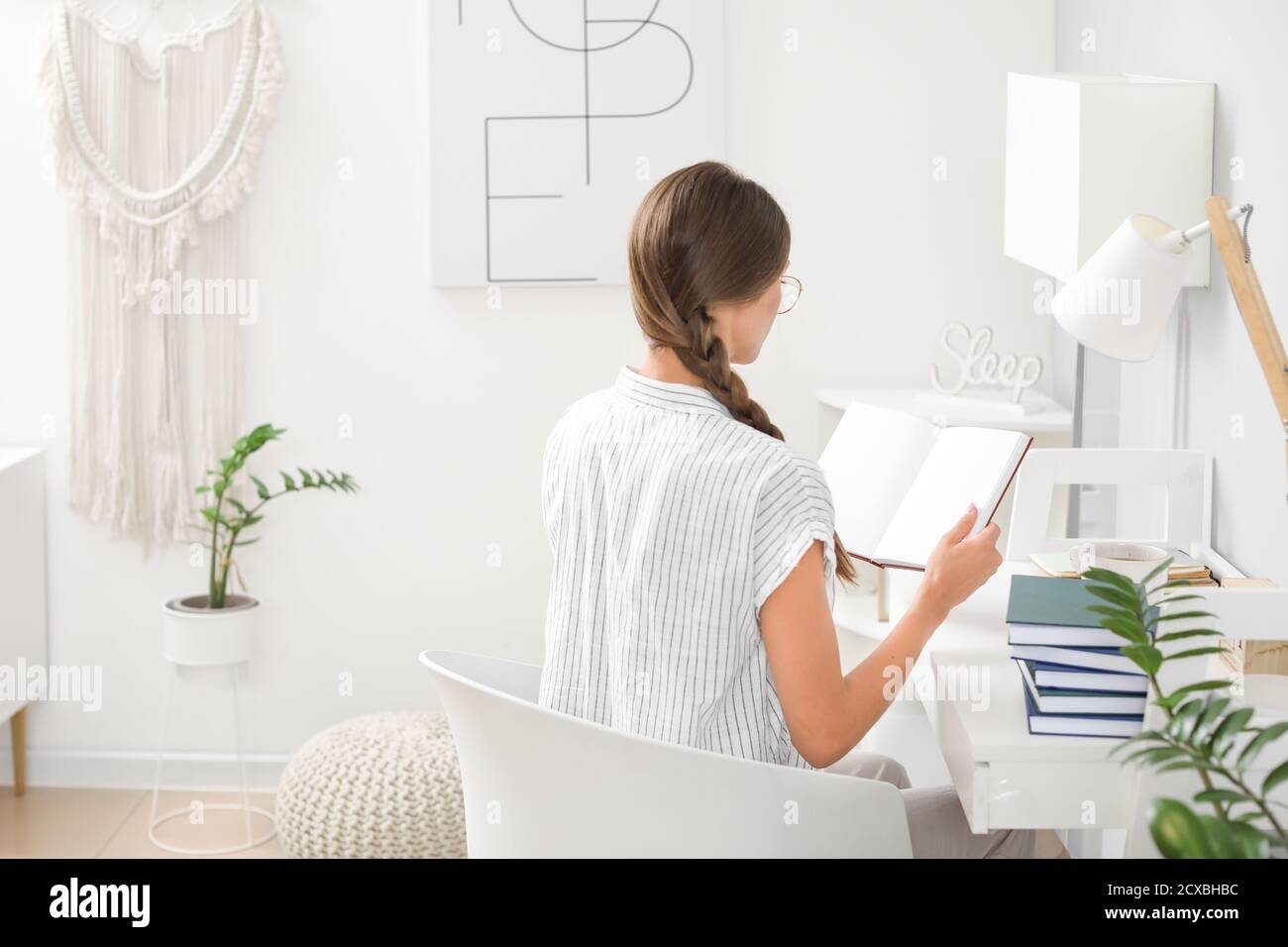 Beautiful young woman reading book at home Stock Photo - Alamy