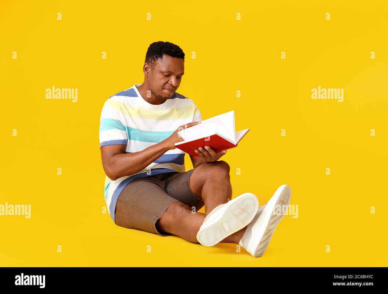 African-American man reading book on color background Stock Photo - Alamy