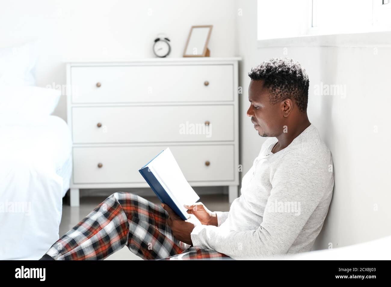 African-American man reading book at home Stock Photo - Alamy