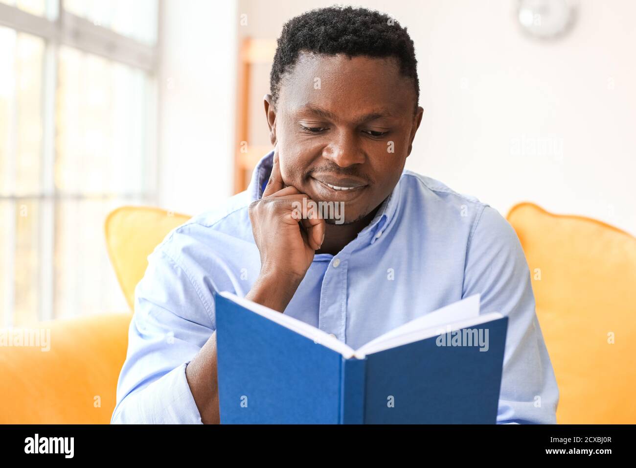 African-American man reading book at home Stock Photo - Alamy