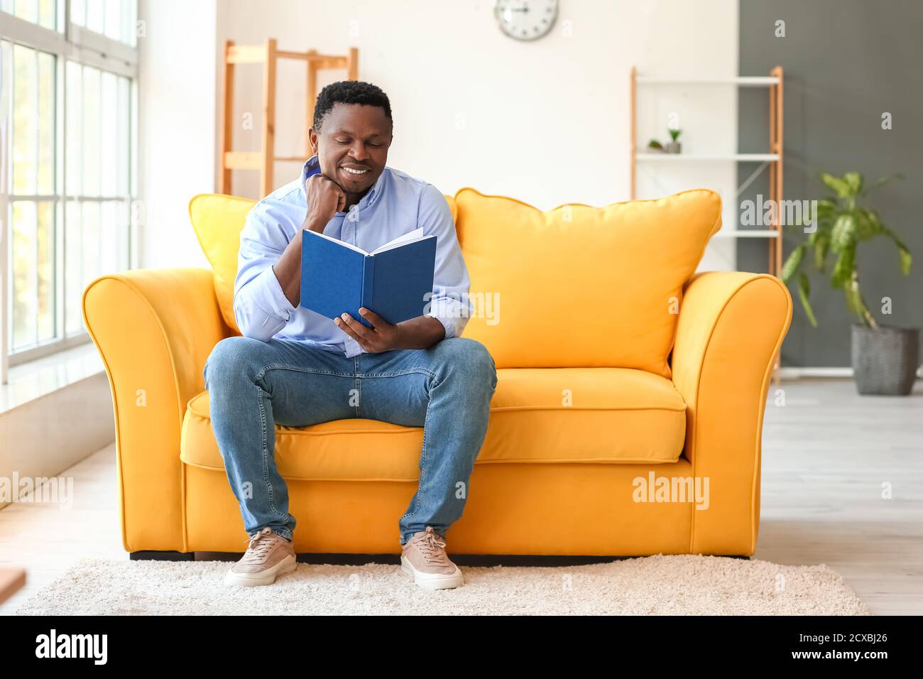 African-American man reading book at home Stock Photo - Alamy