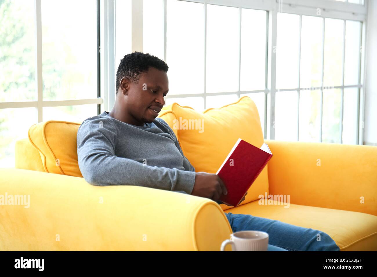 African-American man reading book at home Stock Photo - Alamy