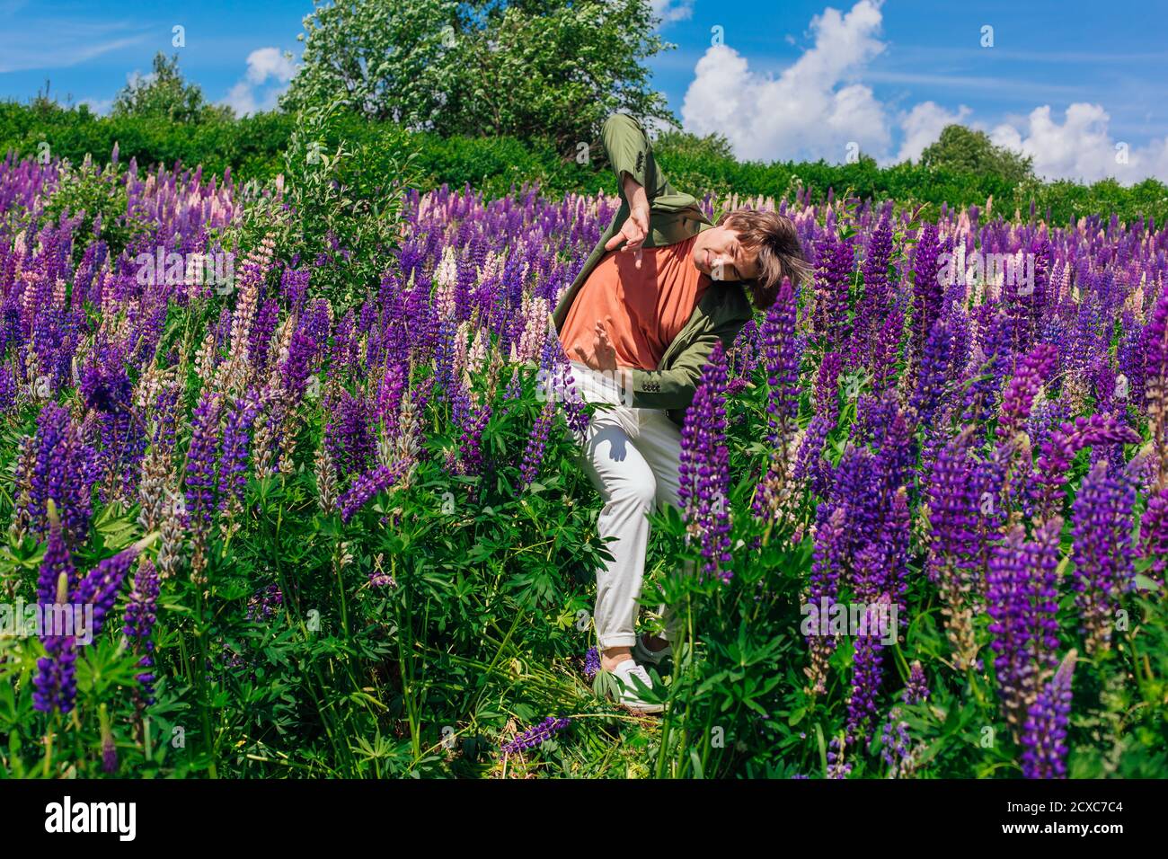 Tall handsome man dancing on lupine flowers field Stock Photo - Alamy