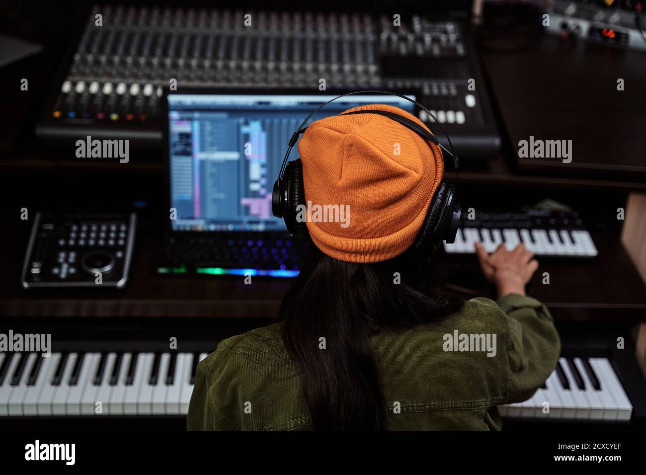 Portrait of beautiful young brunette, female artist playing keyboard ...