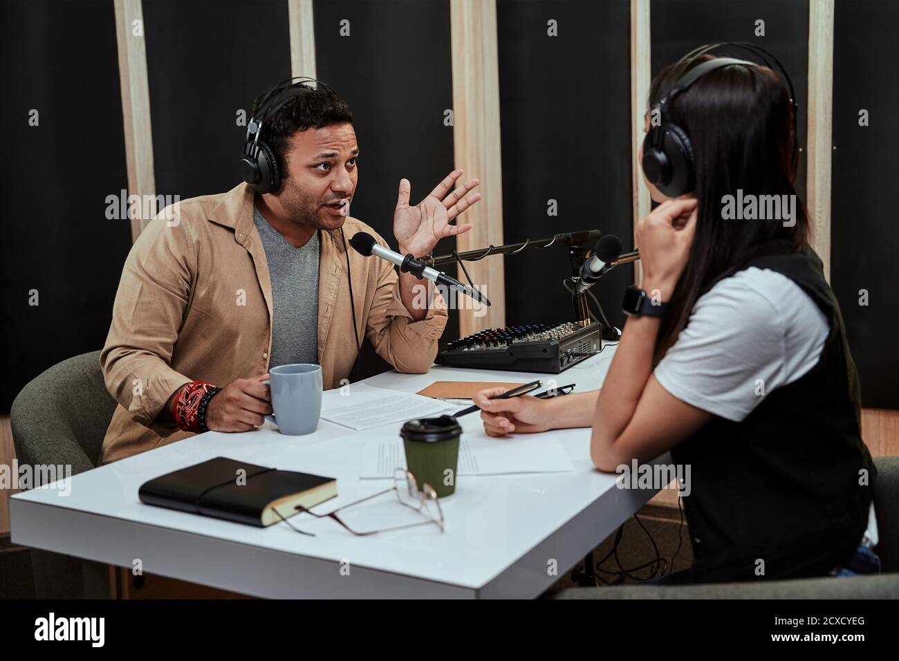 Portait of two radio hosts, man and woman talking with each other while ...