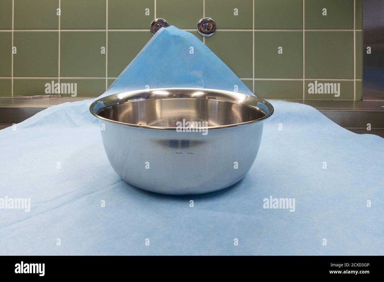 a large silver saline bowl is wrapped in a blue paper towel in an ...