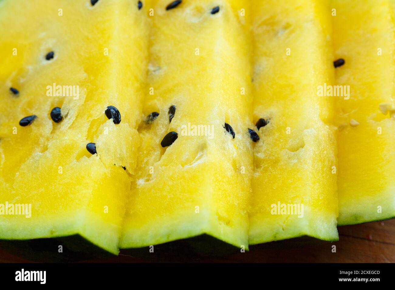 Several slices of watermelon with yellow pulp and black seeds inside ...