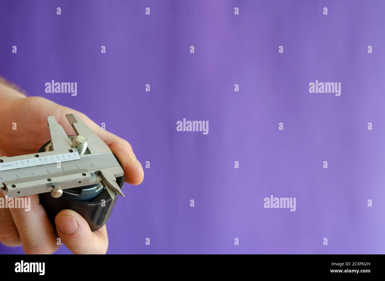 Vernier caliper and timing belt tensioner in hand on blue background ...