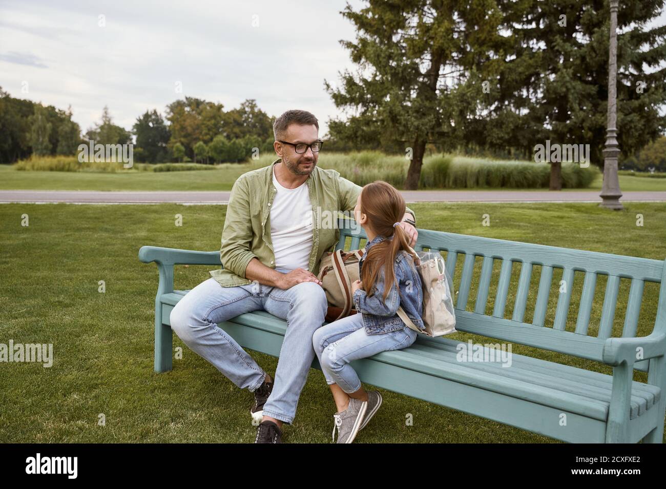 Family day in nature. Young father and his cute little daughter sitting ...