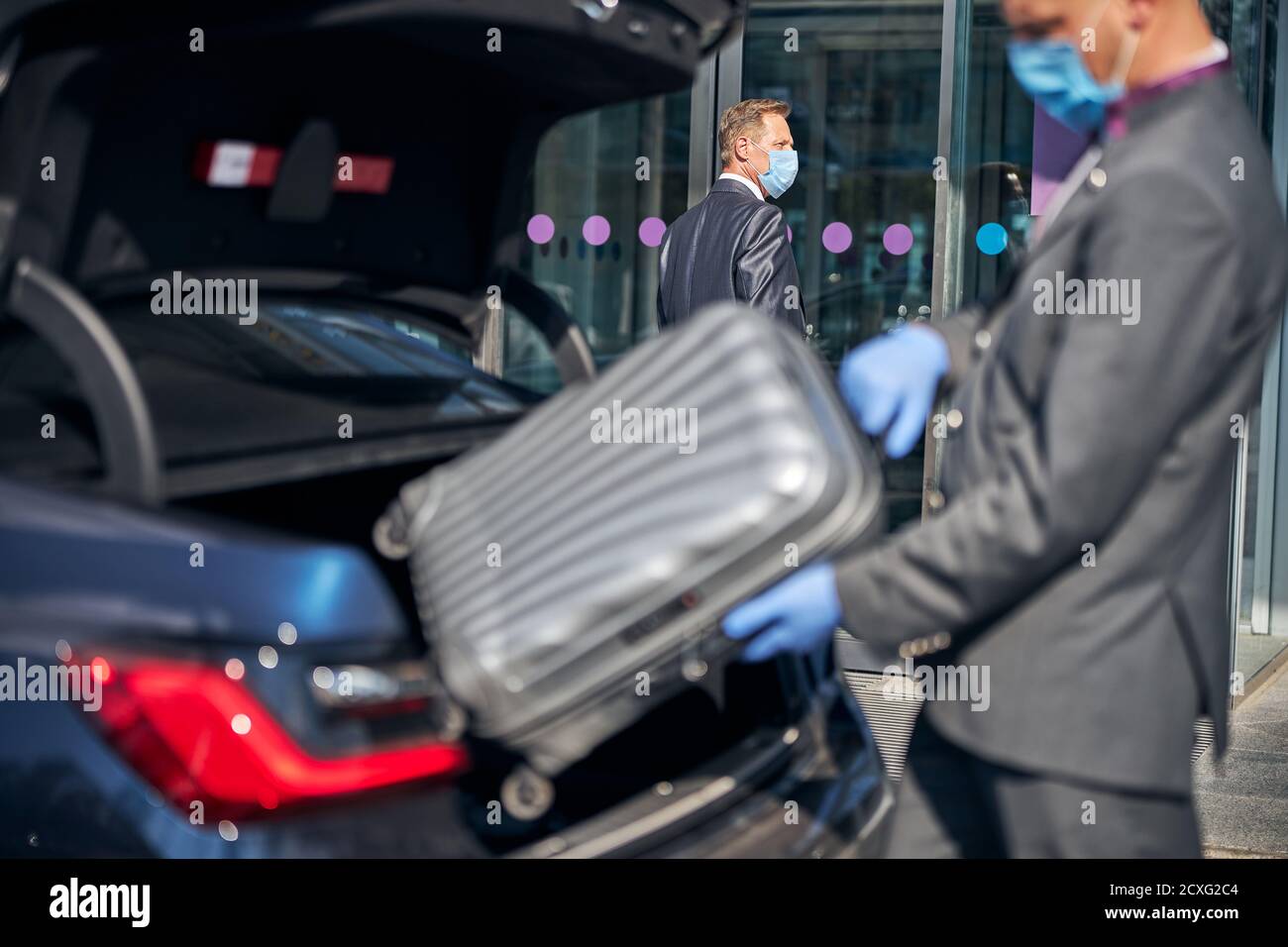Elegant driver packing boss baggage into car at airport Stock Photo - Alamy