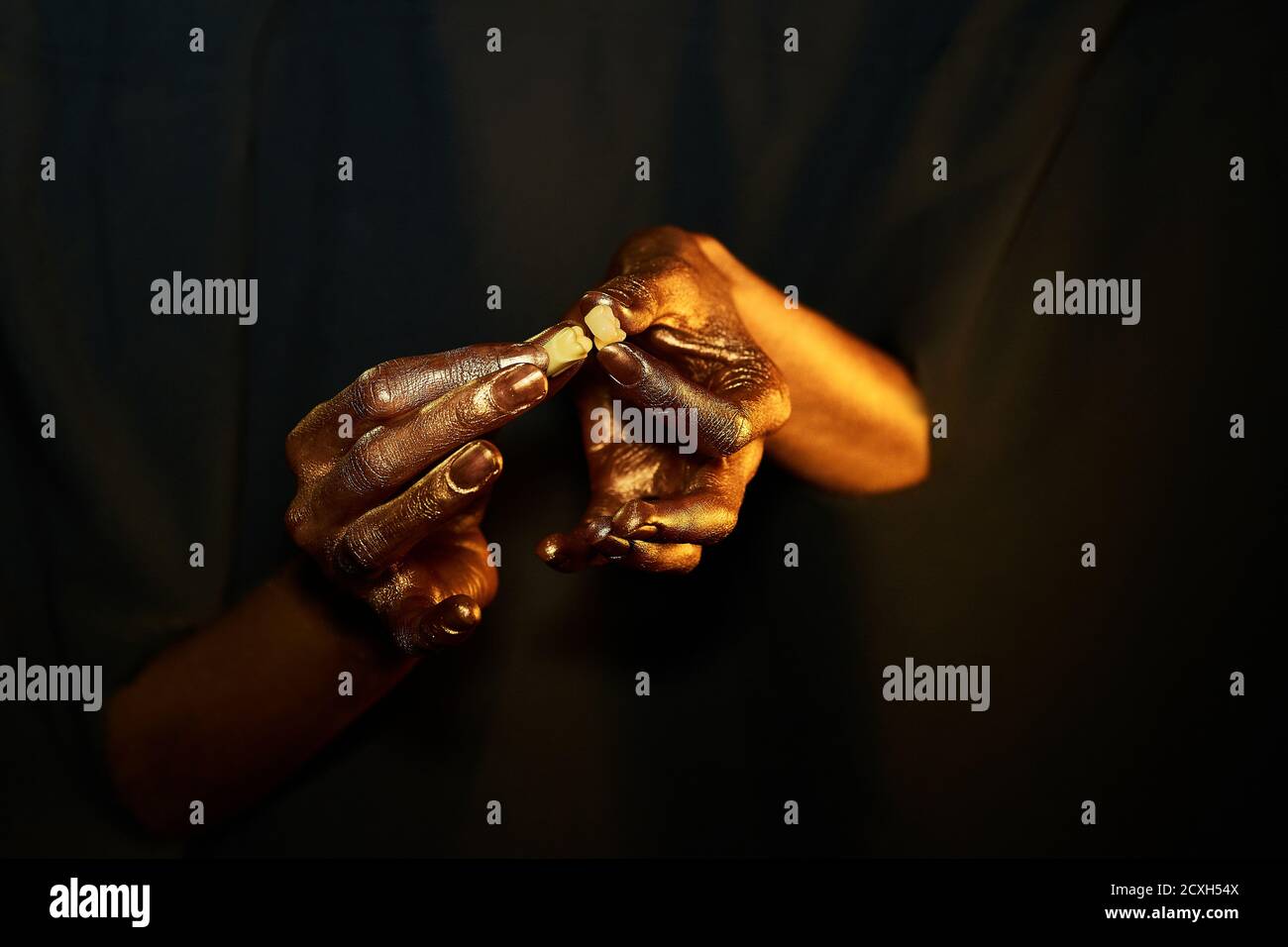 two golden hands holding a tooth and a crown Stock Photo - Alamy