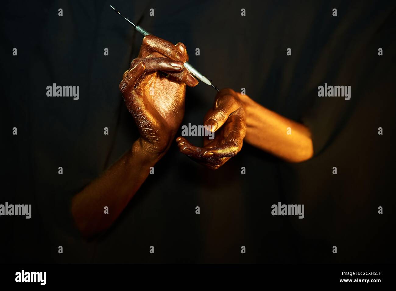 two golden hands with a dental instrument Stock Photo - Alamy