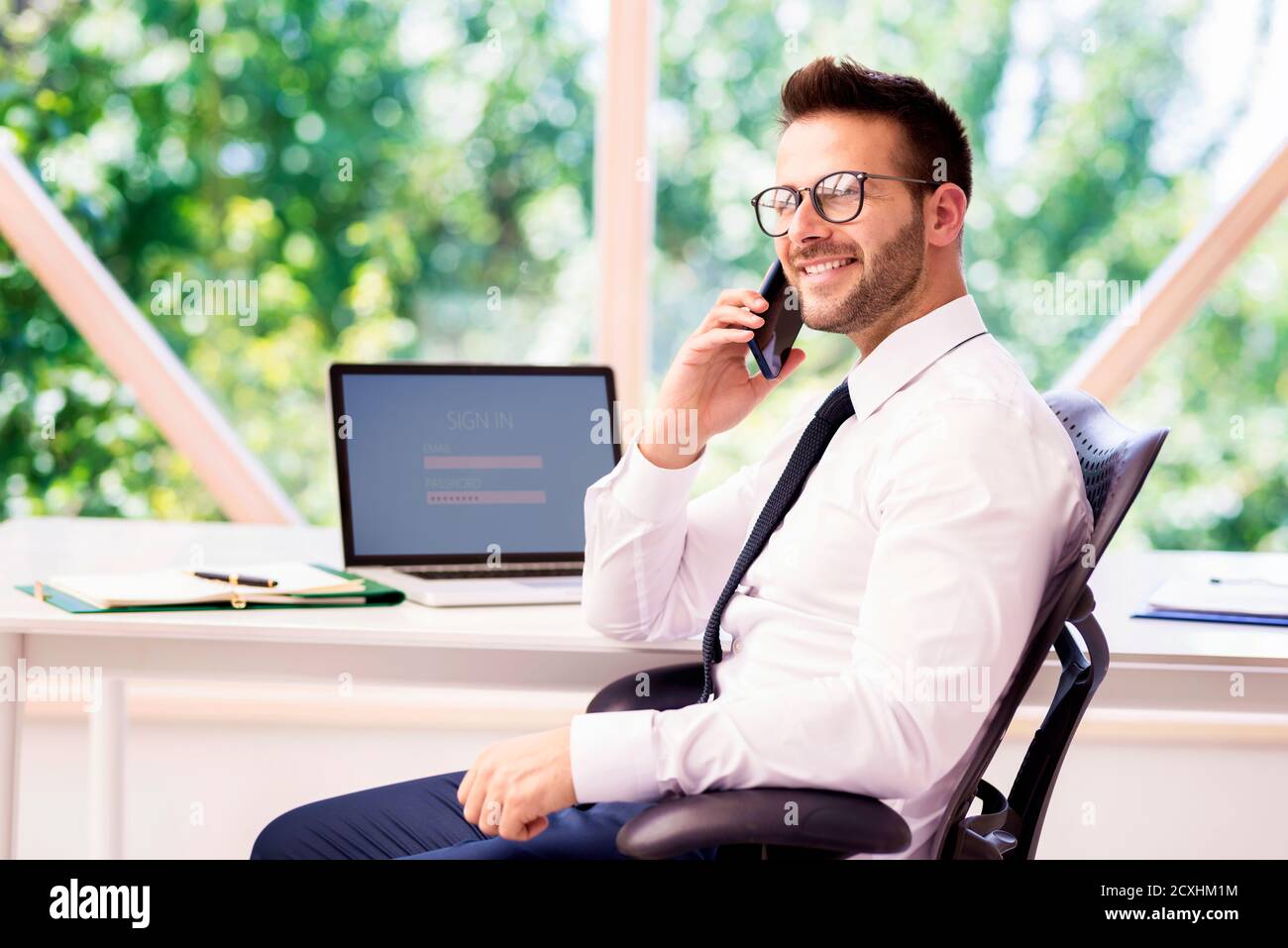 Shot of successful businessman sitting behind his laptop and using ...
