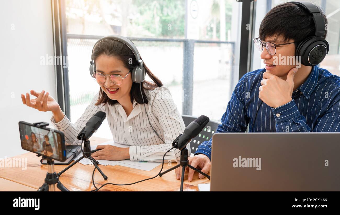 Asian Man and woman podcasters in headphones recording content with ...