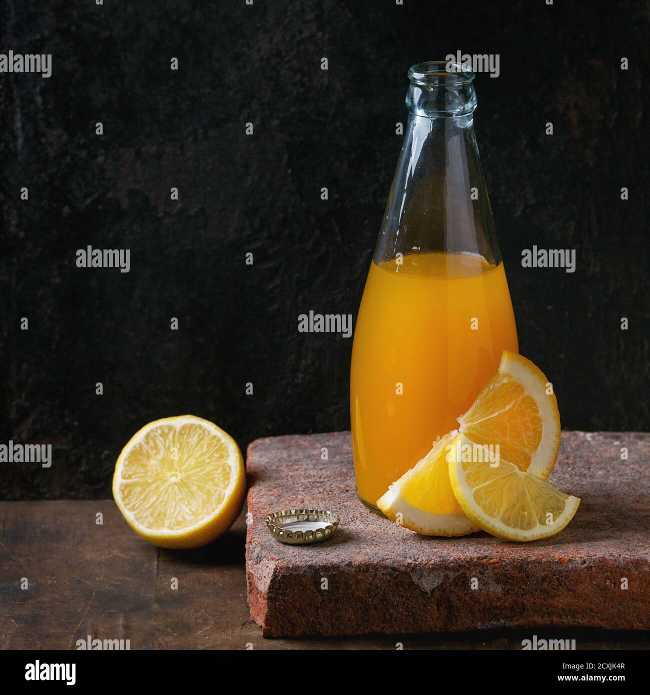 Opened glass bottle of citrus orange and lemon lemonade, standing with ...