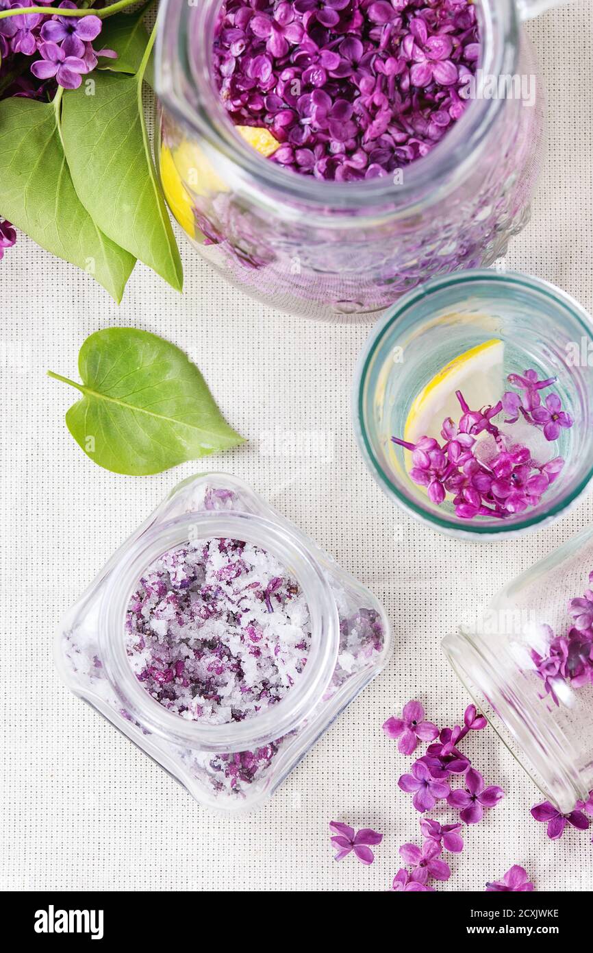Glass jar of lilac flowers in sugar, glass and pitcher of lilac water ...