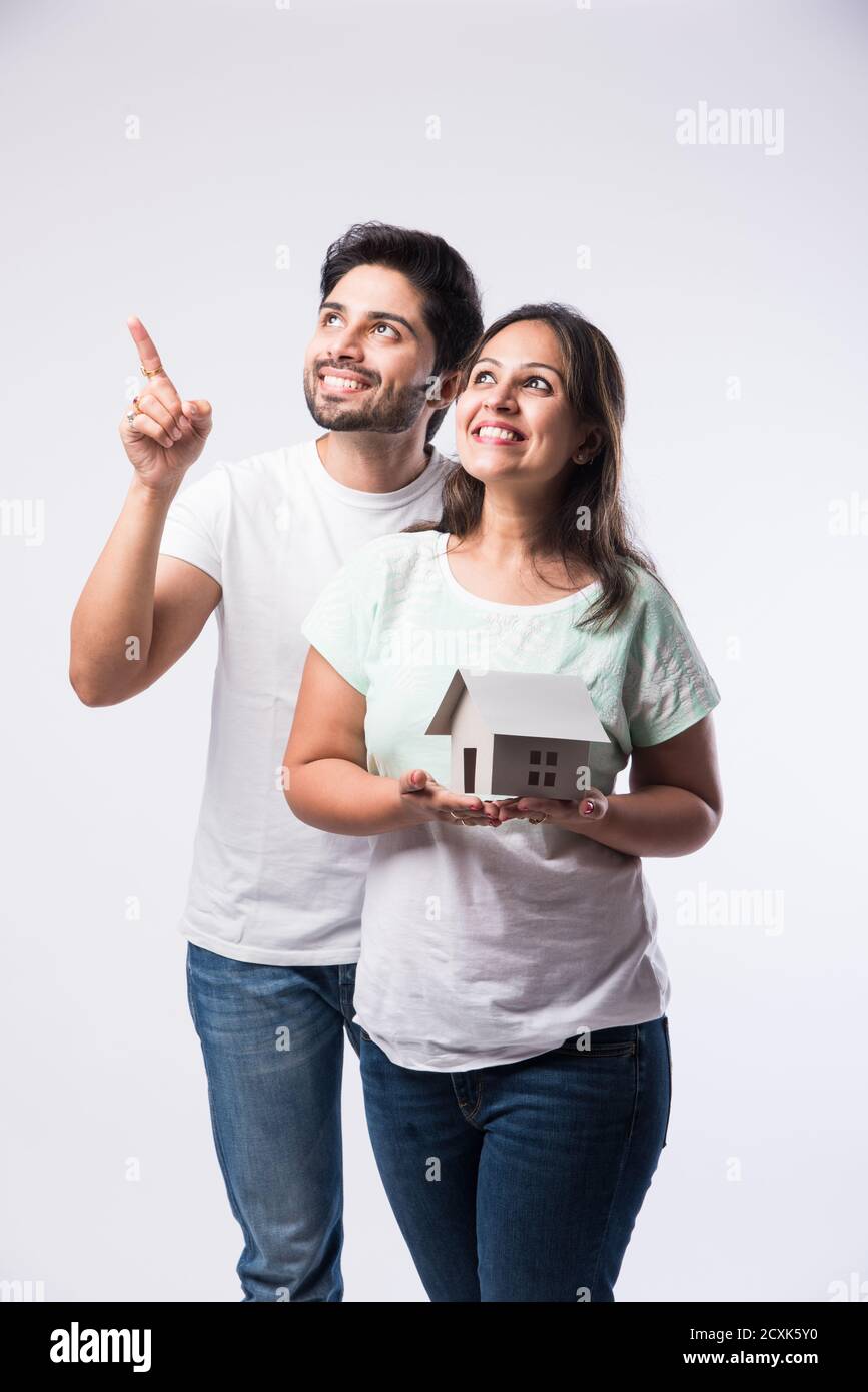 Indian young family couple and real estate concept - buying or rental, standing against white ...