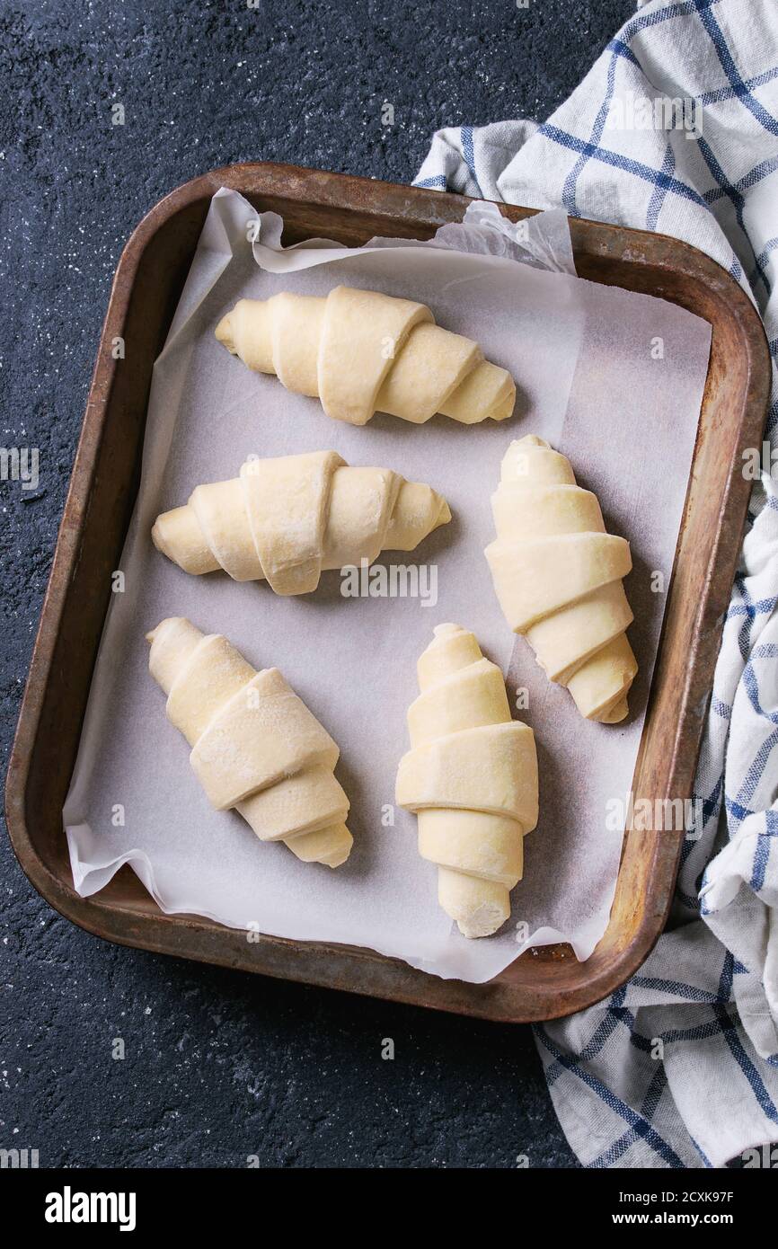 Raw unbaked croissant on baking paper in old oven tray with kitchen ...