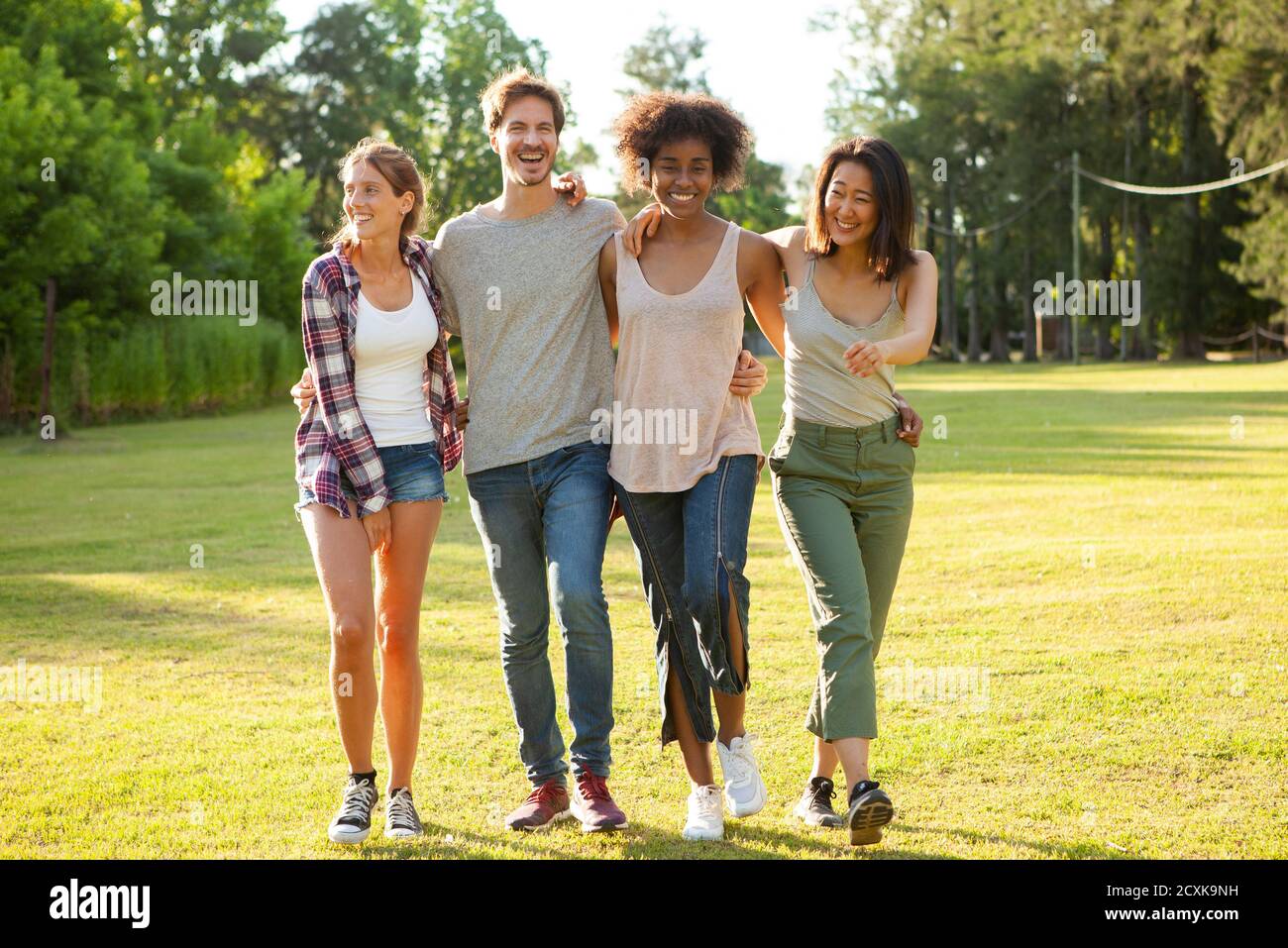 Happy young friends walking together in park Stock Photo - Alamy