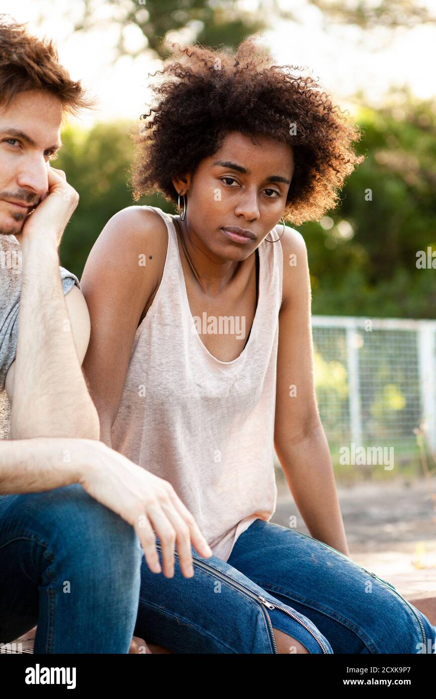 Young friends sitting together in park Stock Photo - Alamy