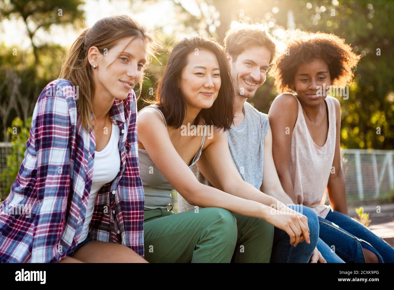 Group of young friends sitting together in park Stock Photo - Alamy
