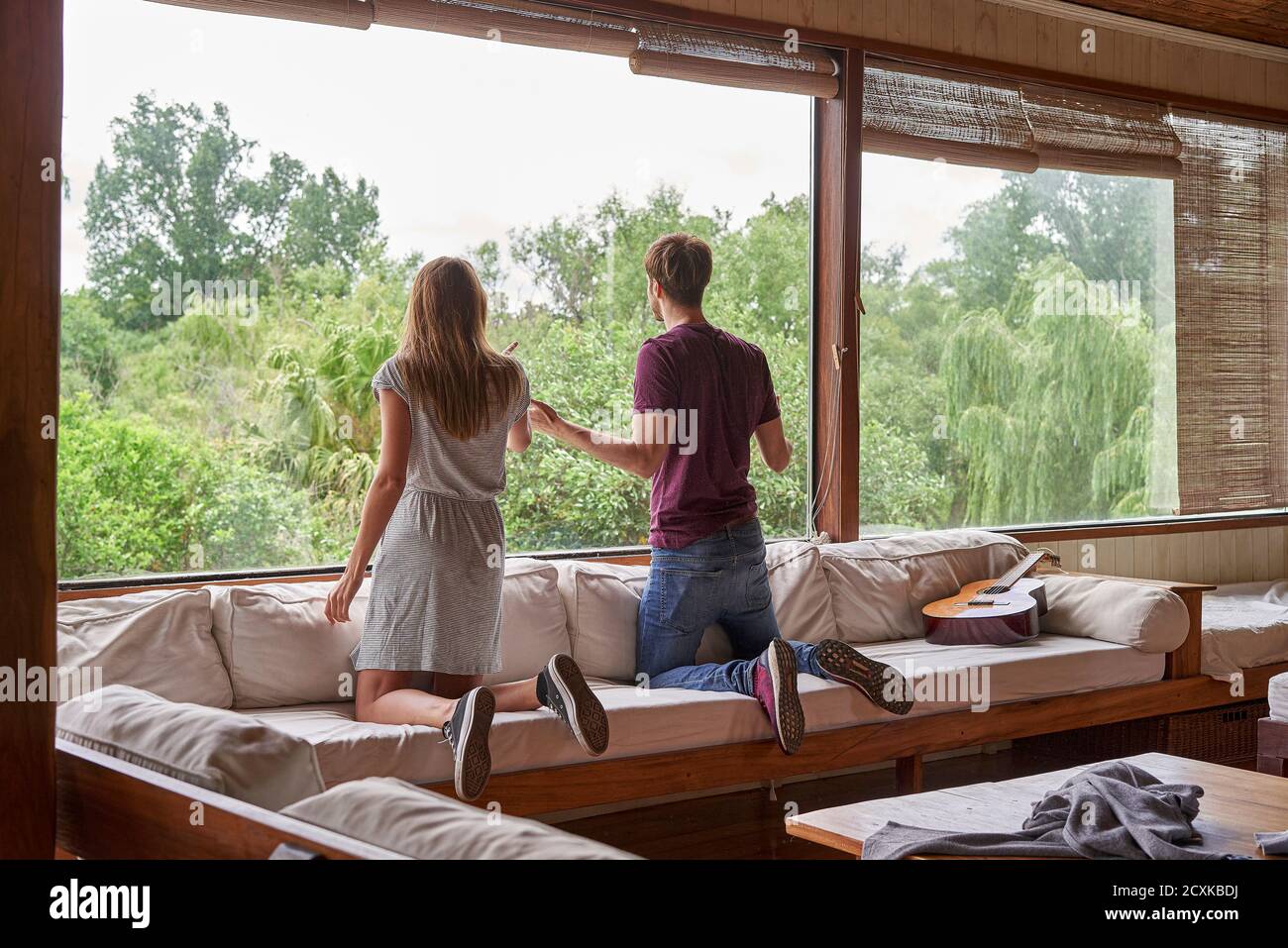 Young couple looking out through window Stock Photo - Alamy