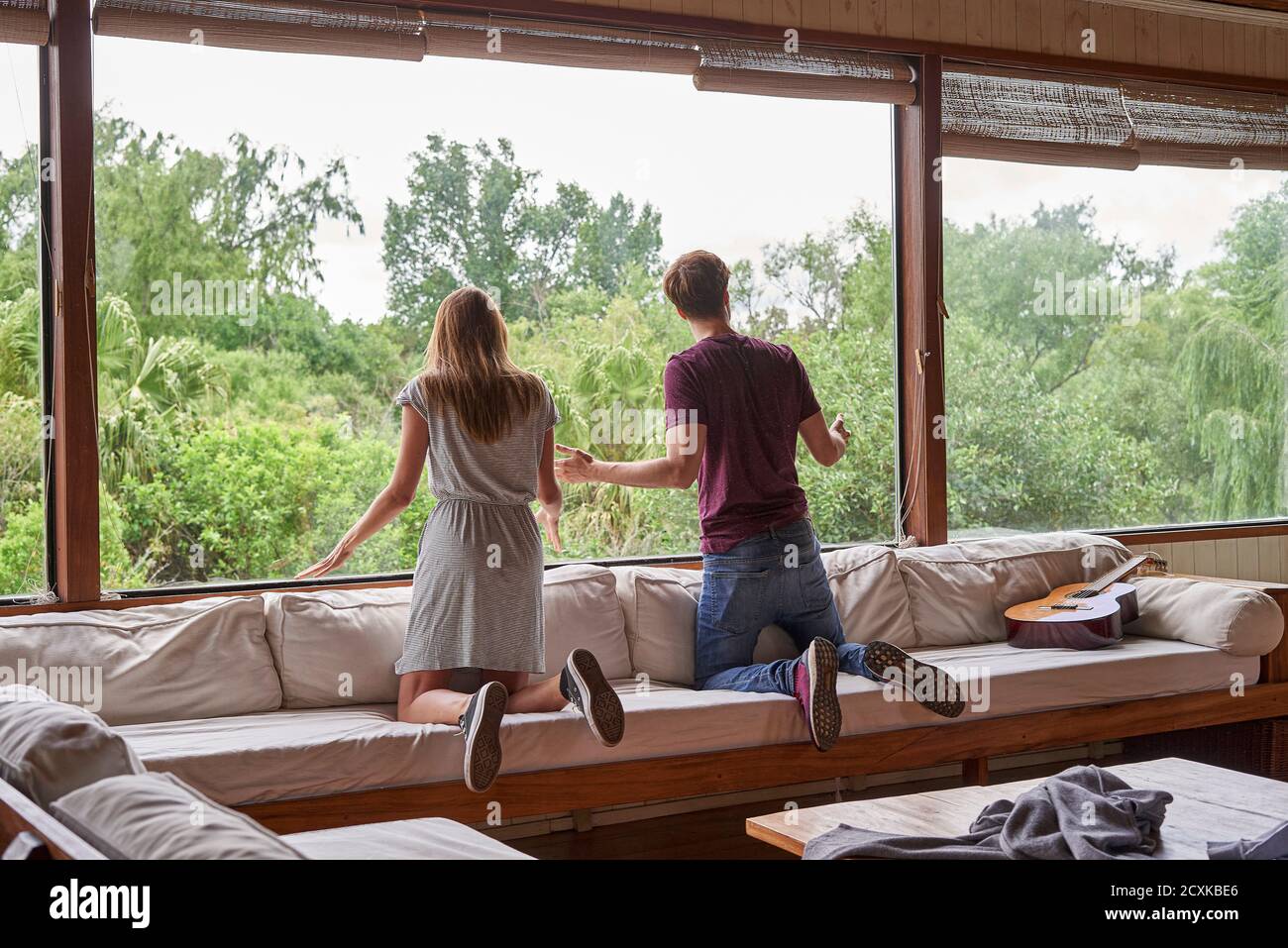 Young couple looking out through window Stock Photo - Alamy
