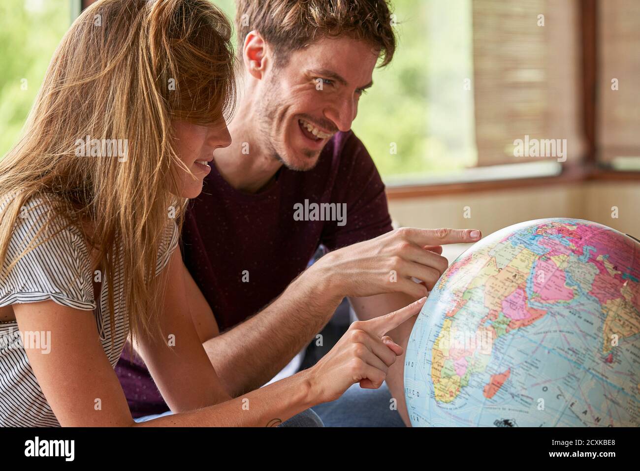 Young couple exploring world globe while sitting on sofa Stock Photo ...