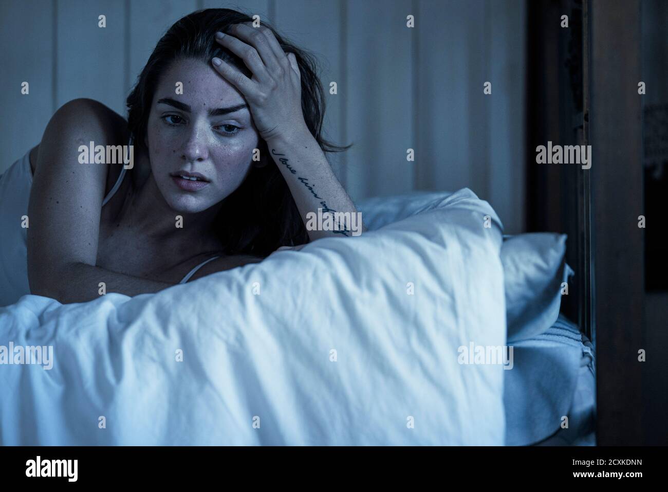 Sad young woman lying on bed Stock Photo - Alamy