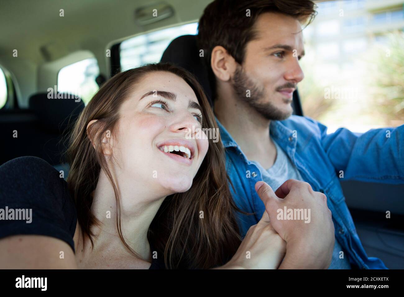 Cheerful young couple holding hands in car Stock Photo - Alamy