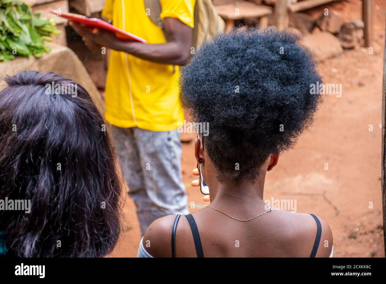 back view of a young african lady with an afro bun using her phone ...