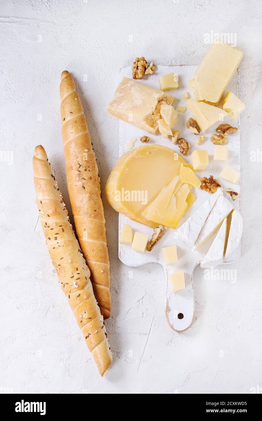 Cheese plate. Assortment of cheese with walnuts and bread on white wood ...