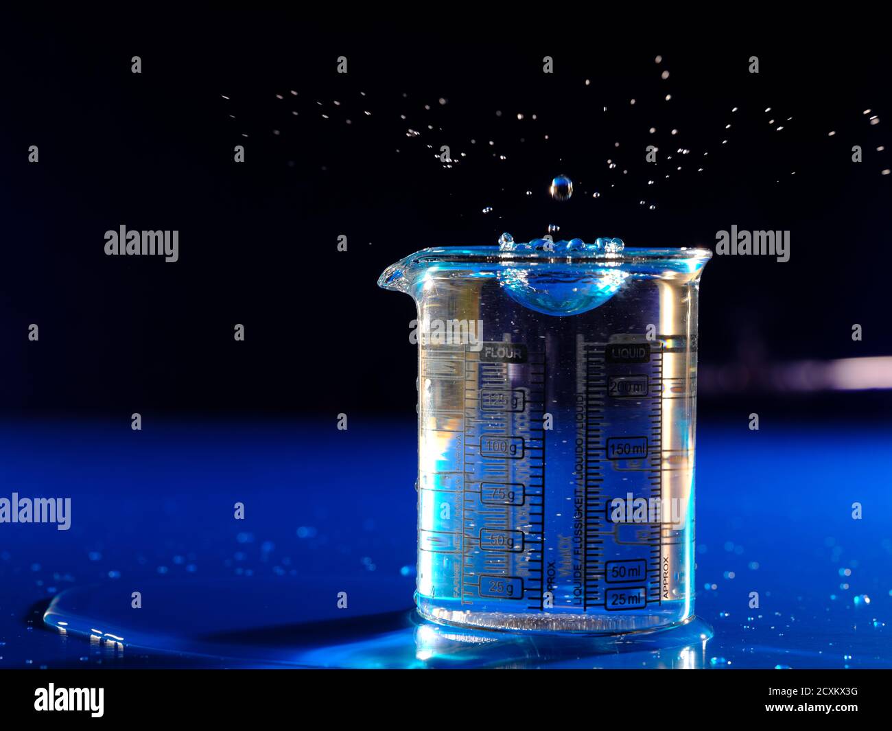 Abstract concept images of water droplets into lab beaker on a blue ...