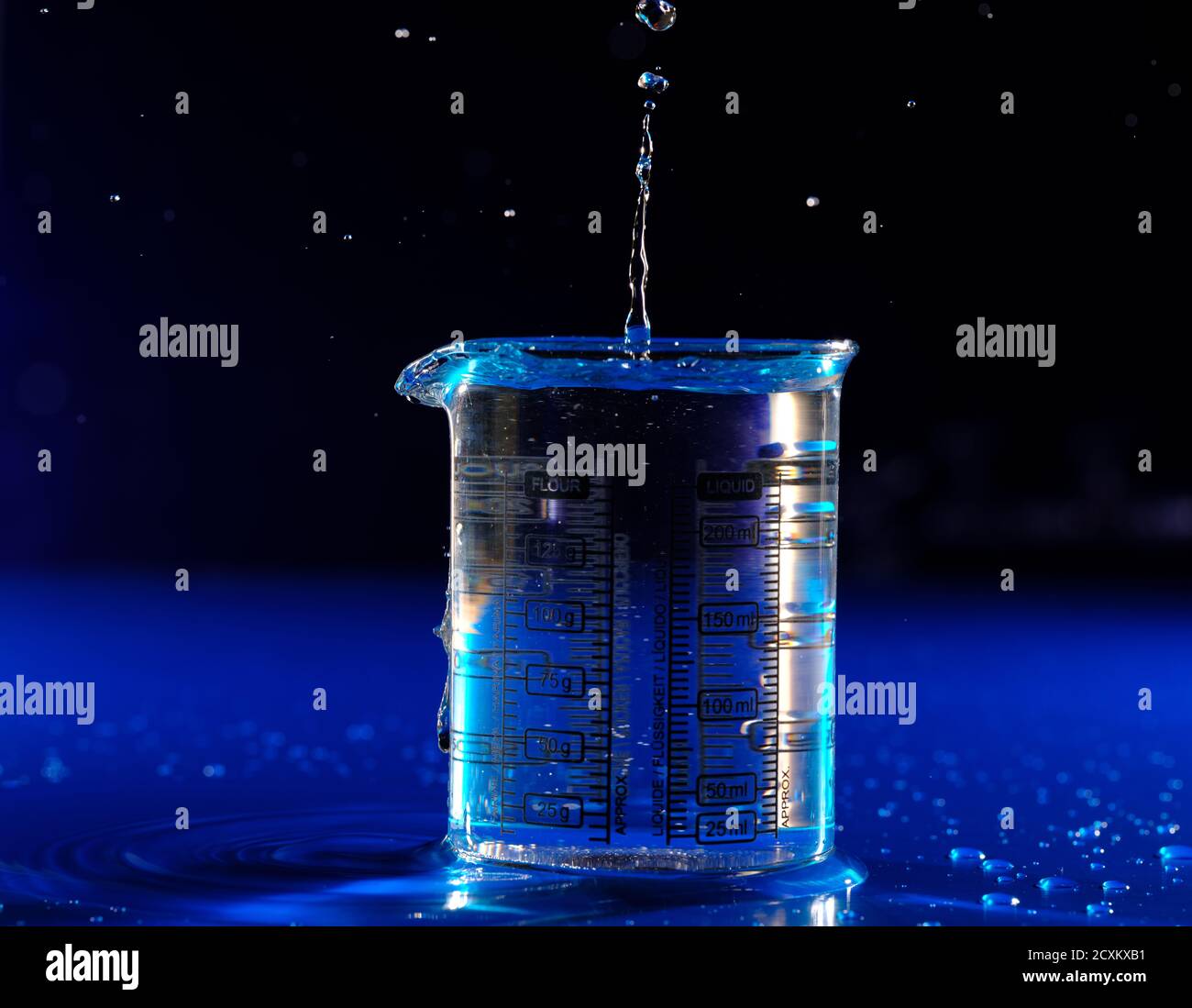 Abstract concept images of water droplets into lab beaker on a blue ...