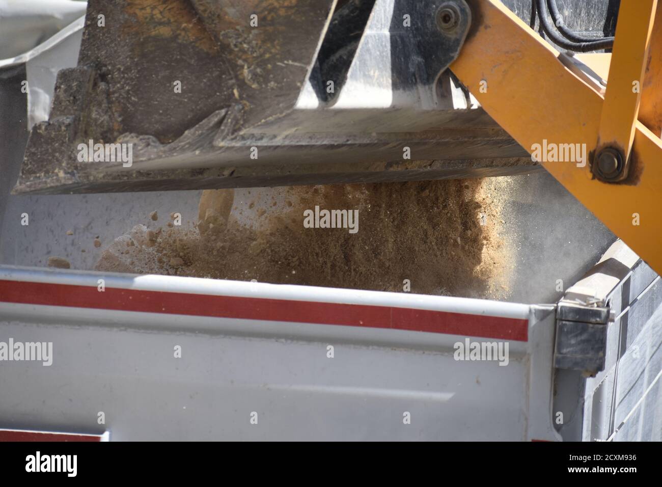 Digger Bucket Emptying Dirt into Dump TruckII Stock Photo - Alamy
