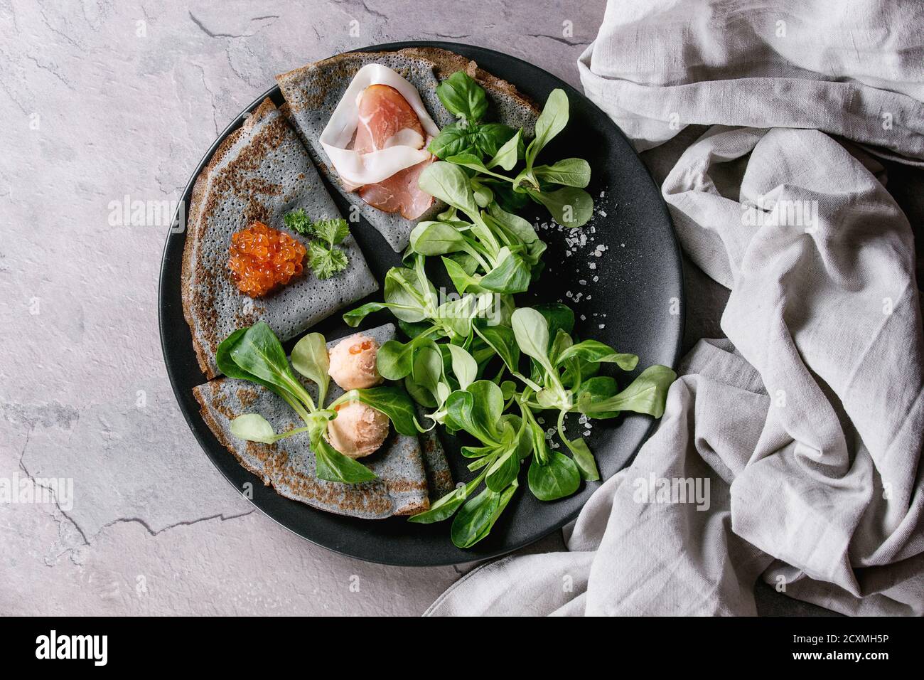 Black pancakes crepes with variety of salt filling red caviar, ham ...