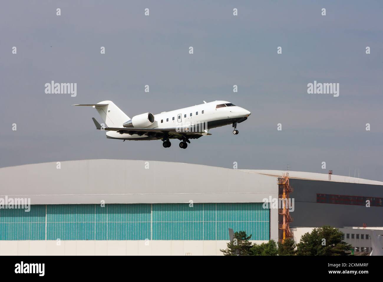 Business jet taking off on the background of a hangar Stock Photo - Alamy