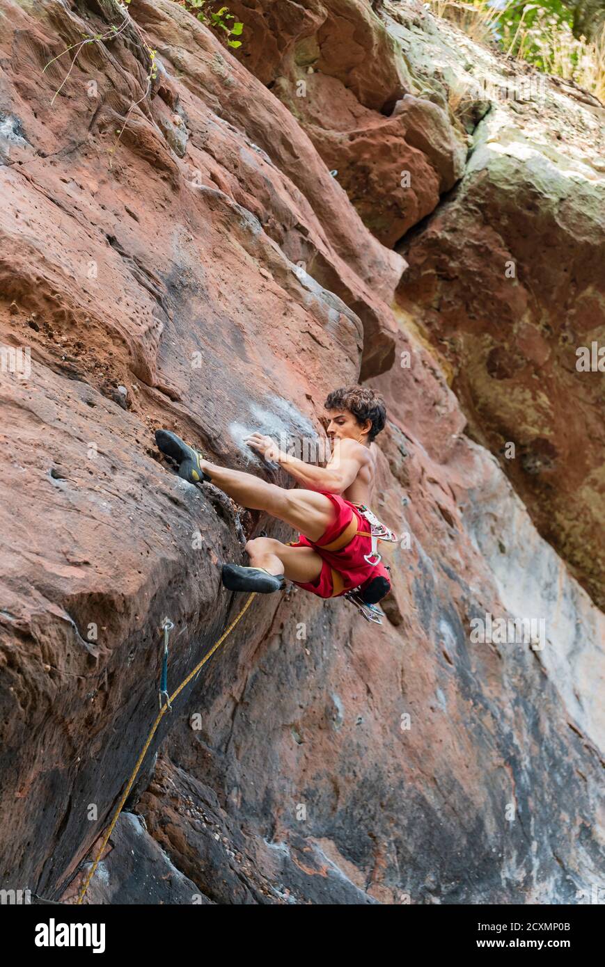 Young man climbs on the ridge of a sandstone rock Stock Photo - Alamy