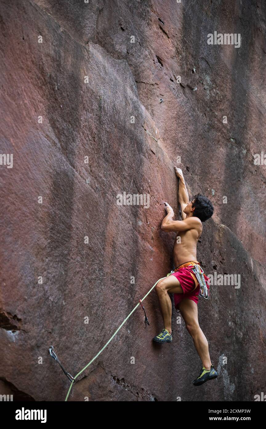Athletic male climber progresses on a climbing route on a colorful ...